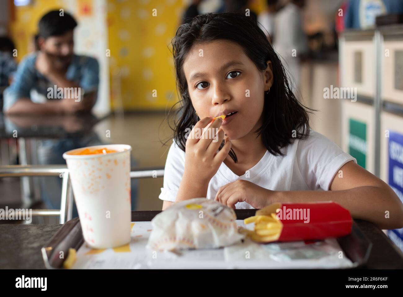 An Indian girl child enjoying meal with fast food in a restaurant Stock ...