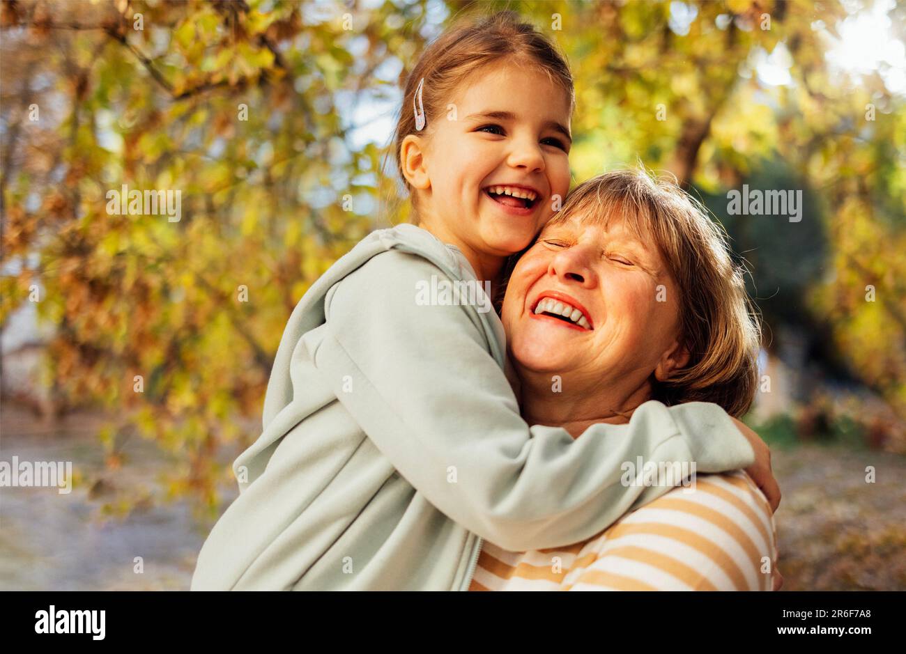 Little girl hugging smiling middle aged woman. Cute female kid and her ...