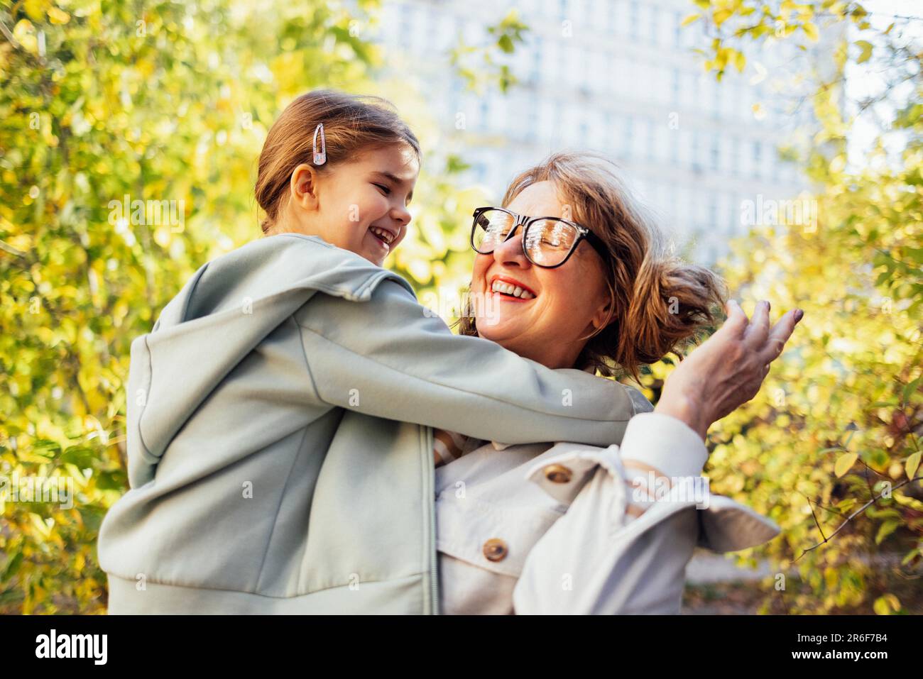 Little girl hugging smiling middle aged woman. Cute female kid and her ...