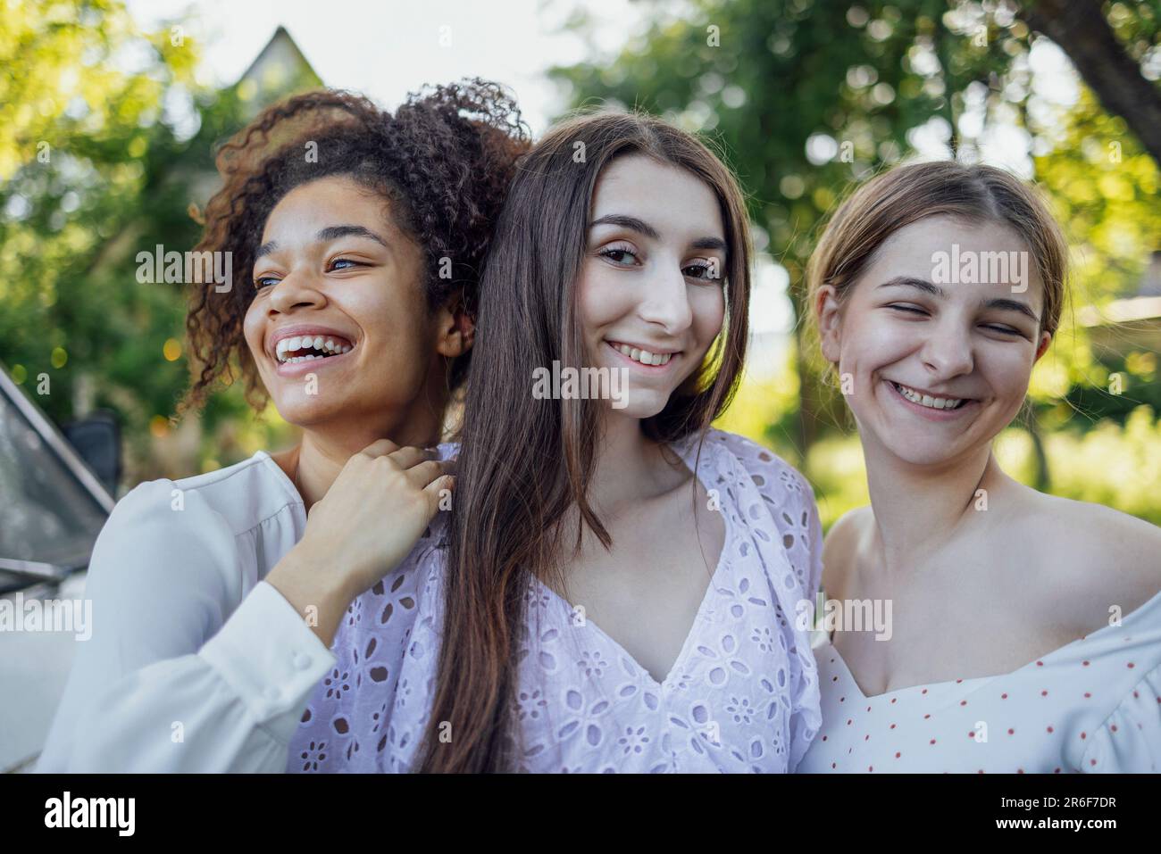 Three pretty female multiracial teenagers in white elegant dresses are ...