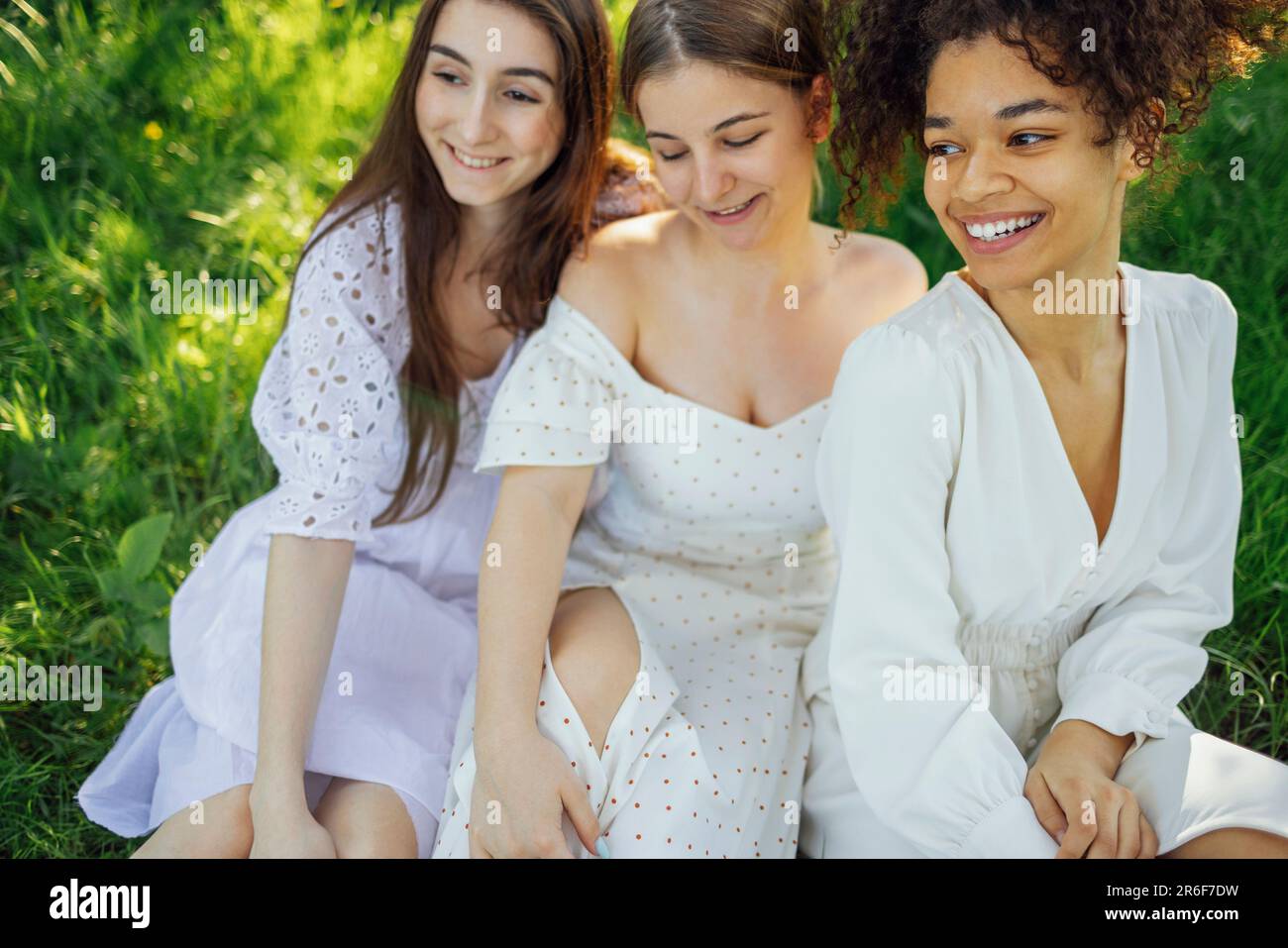 Three cute female teenagers of different nationalities in white elegant ...