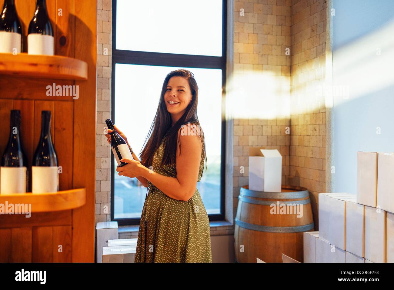 Young charming woman with long beautiful hair smiles and holds a bottle ...