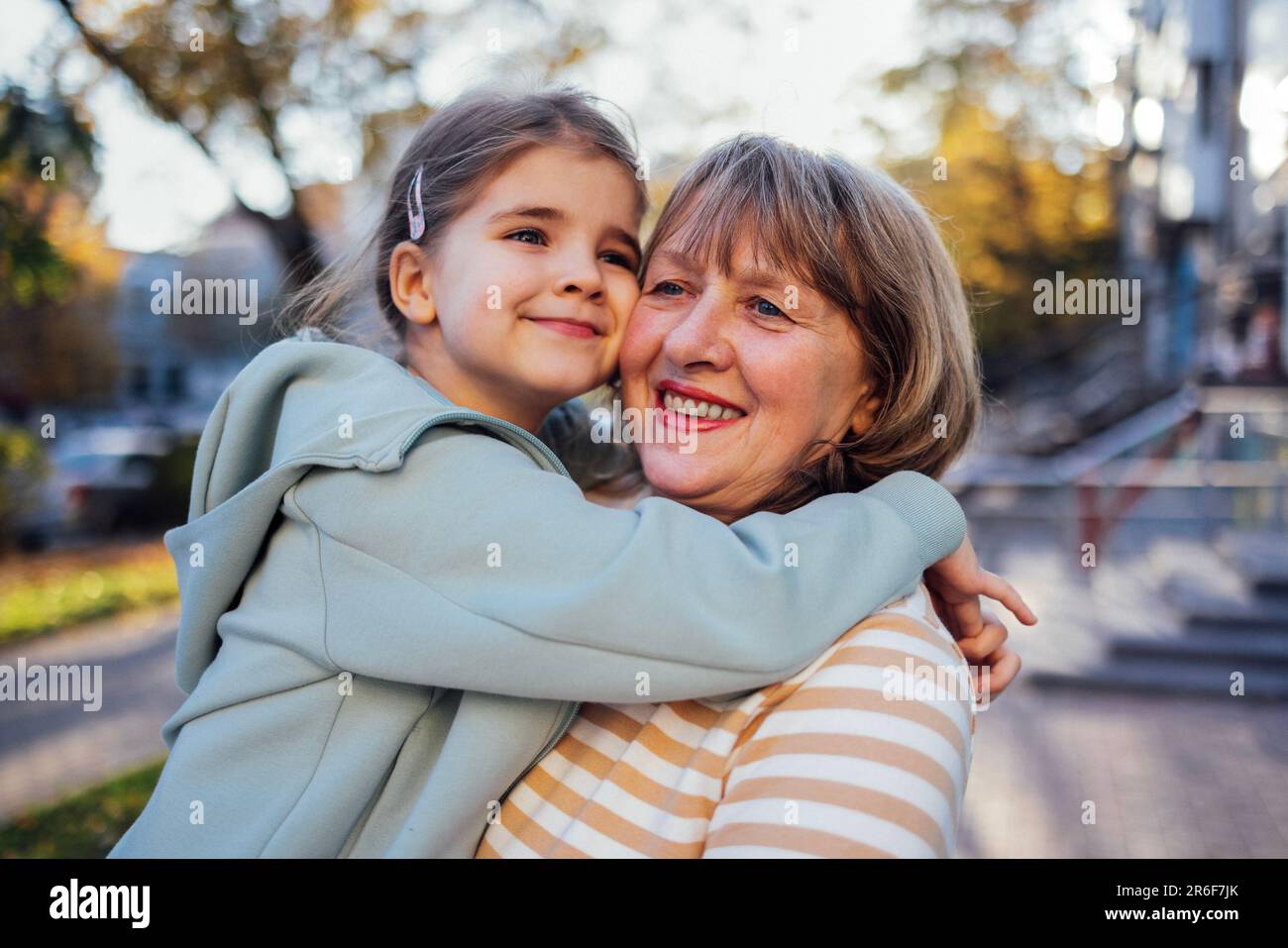 Little girl hugging smiling middle aged woman. Cute female kid and her ...