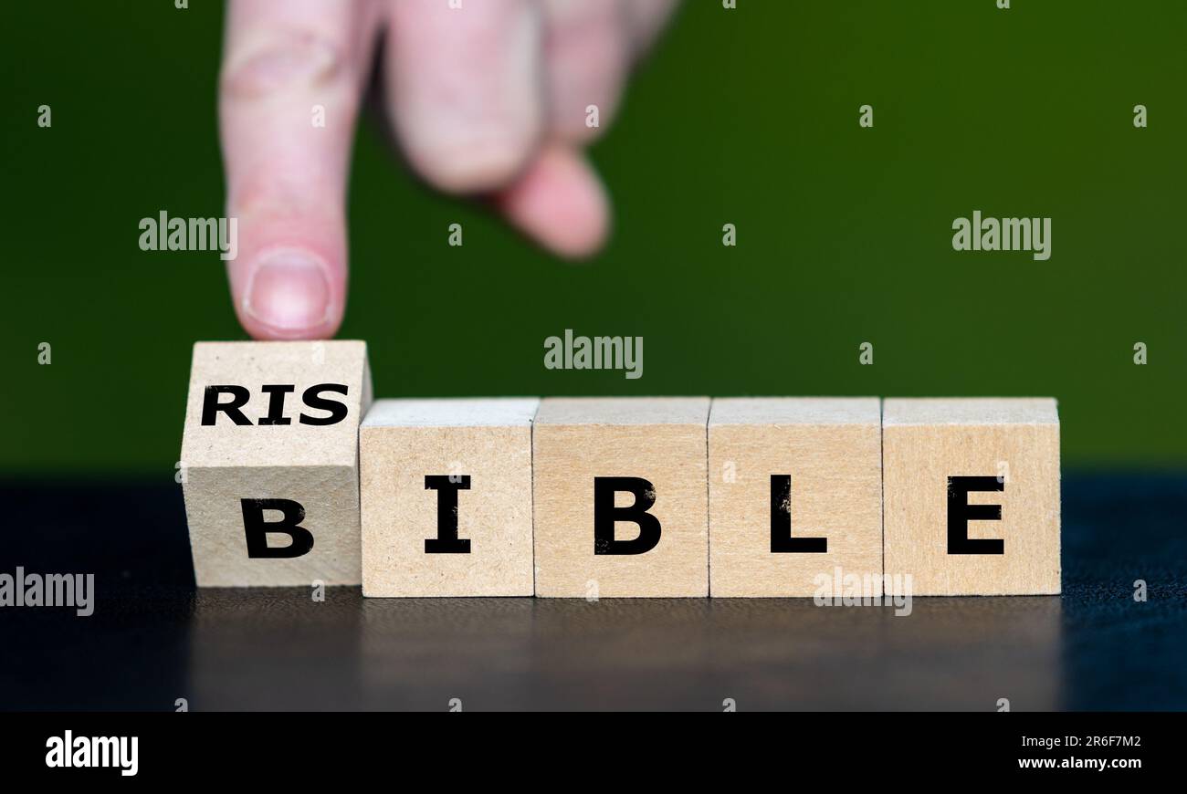 Hand turns wooden cube and changes the word bible to risible. Symbol ...