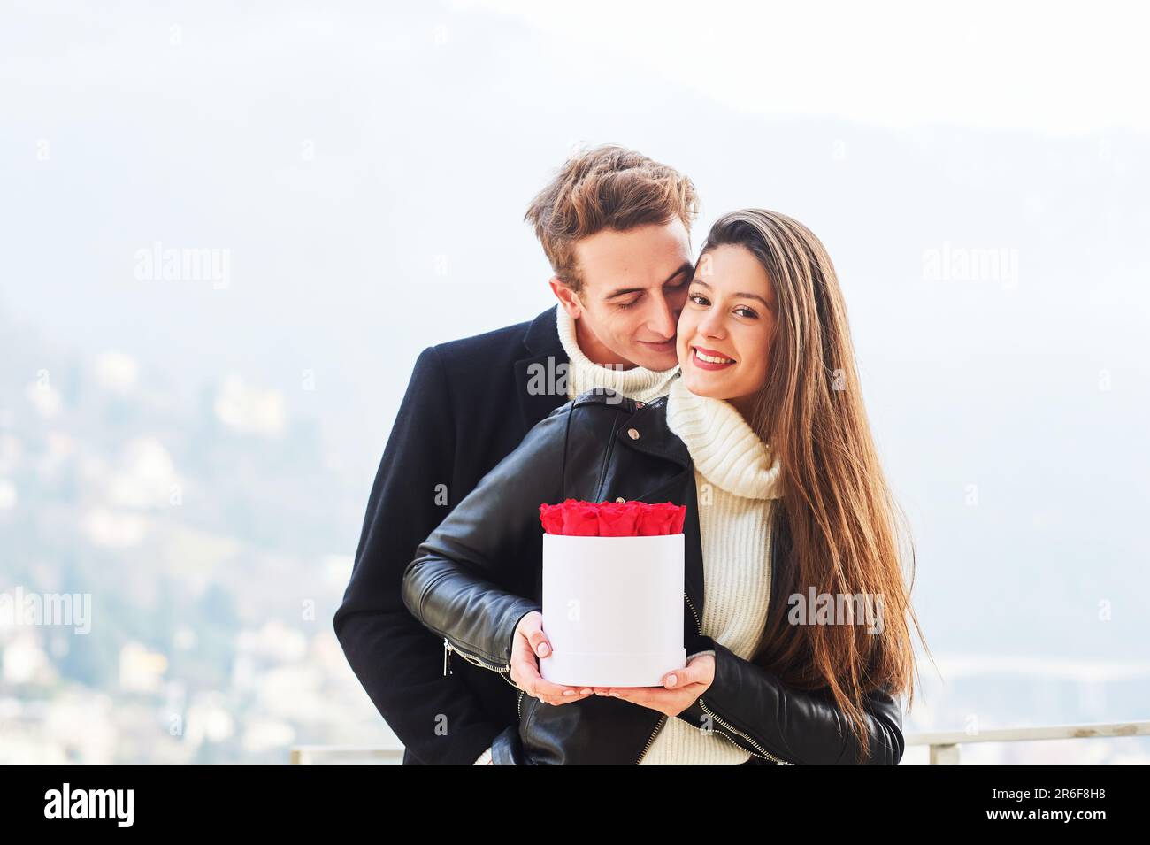 Happy laughing couple, man offering flower box of red roses to ...