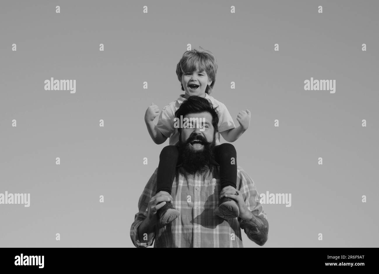 Portrait of happy father giving son piggyback ride on his shoulders ...