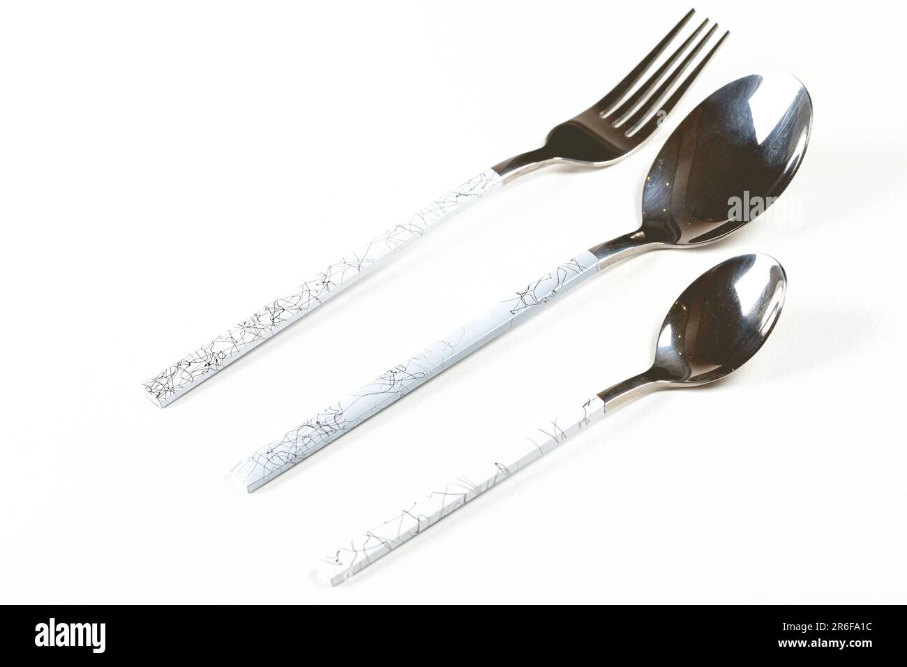 An arranged set of silver fork and two spoons on a white background ...