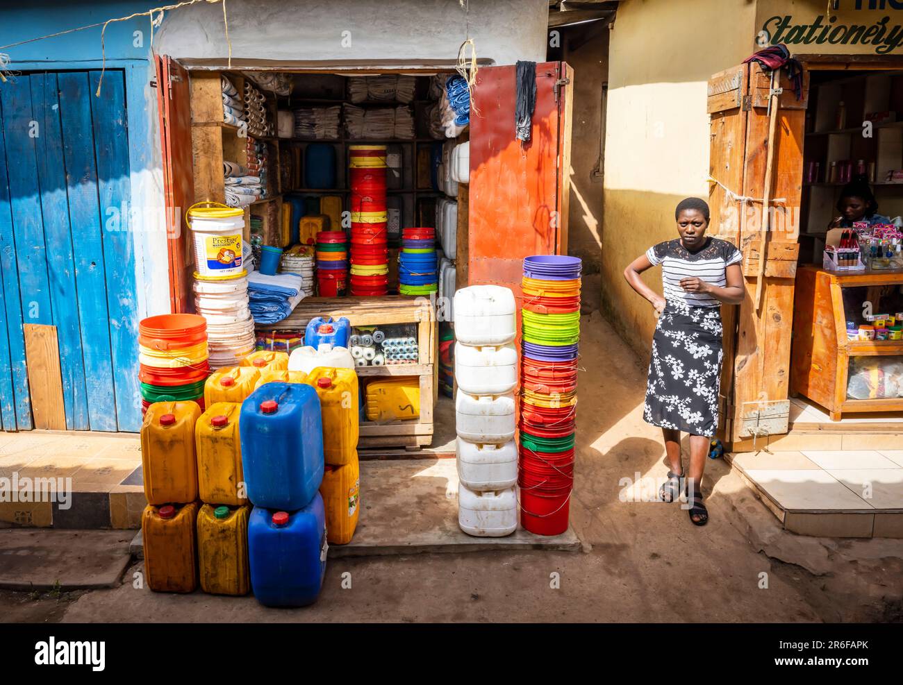 A women market trader in Mzuzu, Malawi, stands outside her plasticware ...