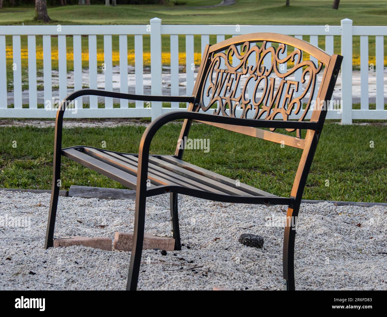 Metal bench in sand with welcome installed in backrest at sunset next ...