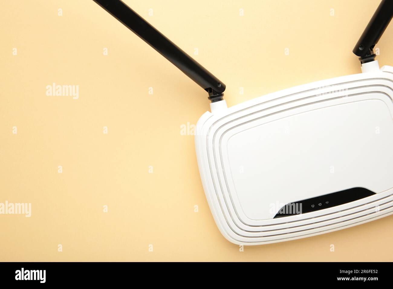 White wi-fi router with black antennas on beige background with copy ...