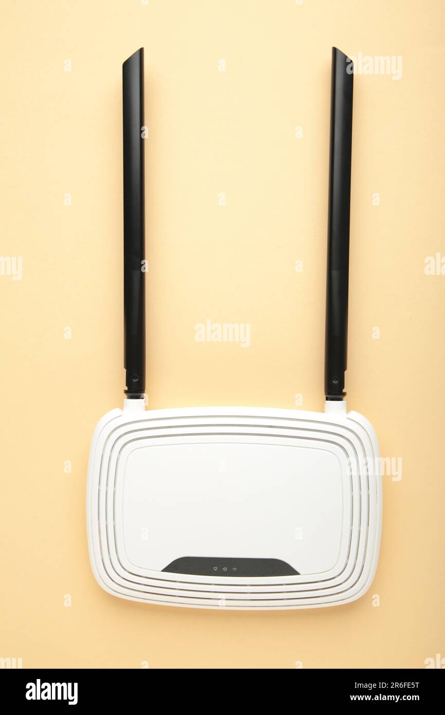 White wi-fi router with black antennas on beige background with copy ...