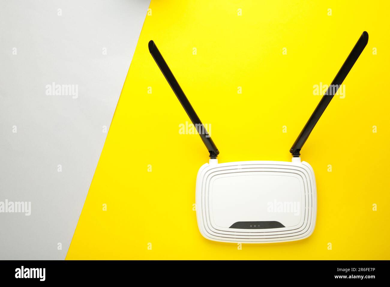 White wi-fi router with black antennas on yellow grey background with ...