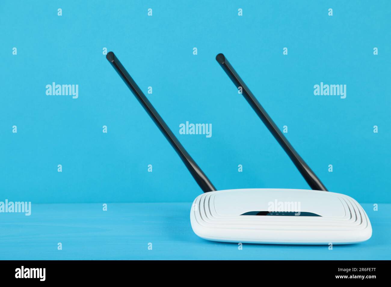White wi-fi router with black antennas on blue background with copy ...