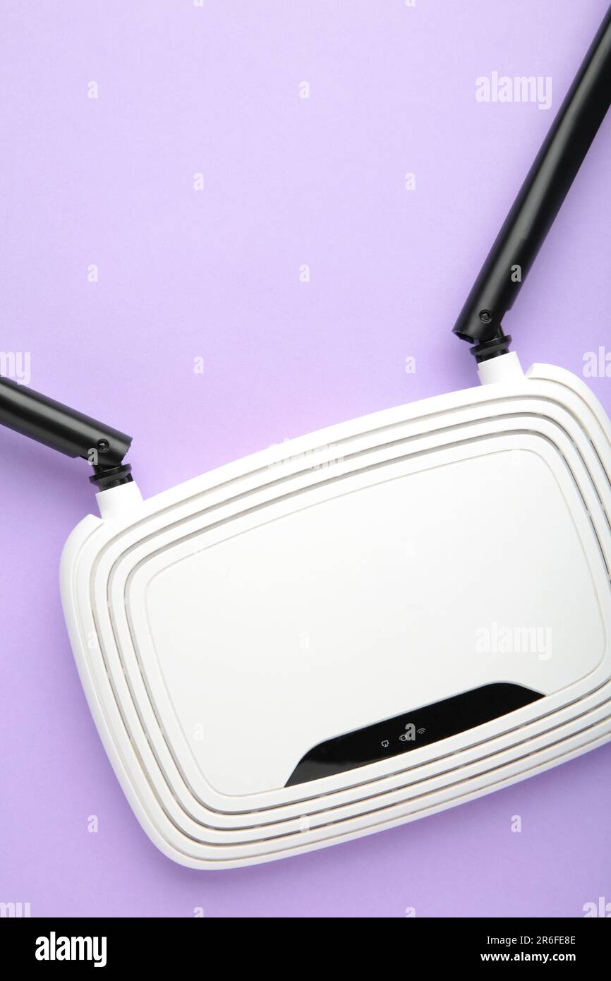 White wi-fi router with black antennas on purple background with copy ...
