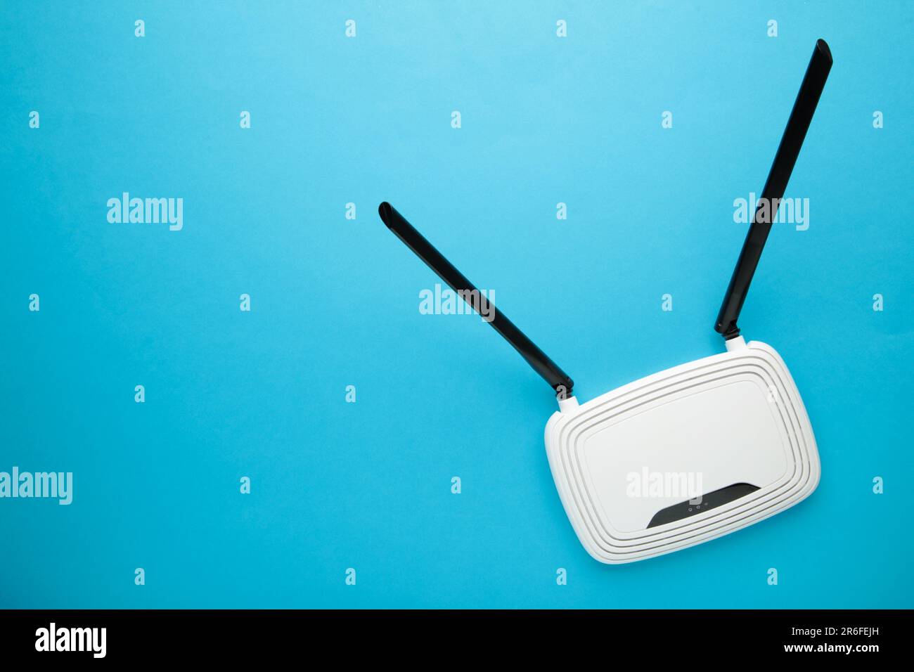 White wi-fi router with black antennas on blue background with copy ...
