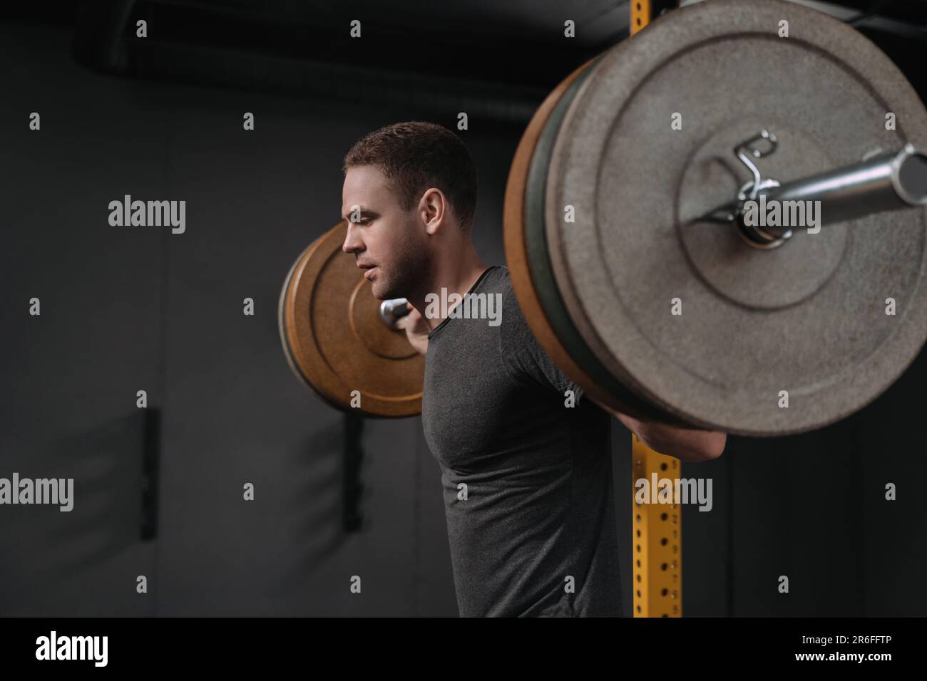 Portrait of male bodybuilder doing back squats in gym. Muscular ...