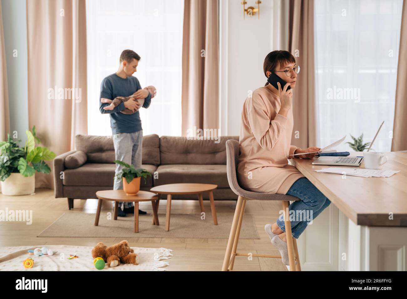 Young woman working remotely at home, using laptop and smartphone in ...