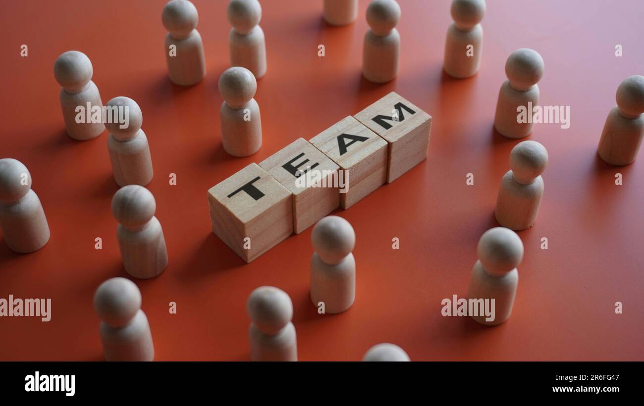 Wooden dolls and text TEAM. Colleague, teamwork, support, cooperation ...