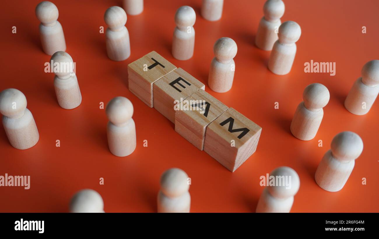 Wooden dolls and text TEAM. Colleague, teamwork, support, cooperation ...