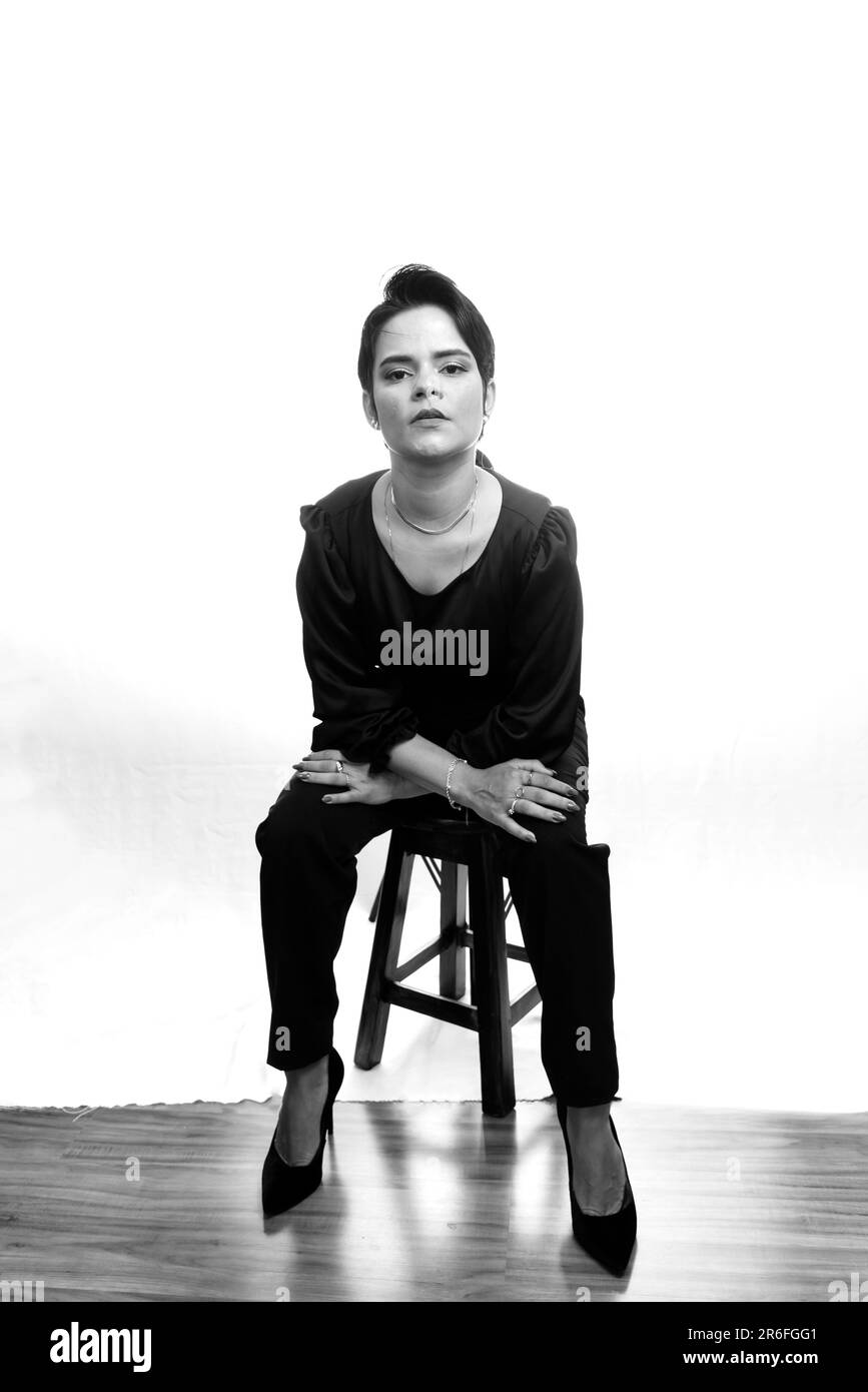 A black and white portrait of an attractive female seated in a chair ...