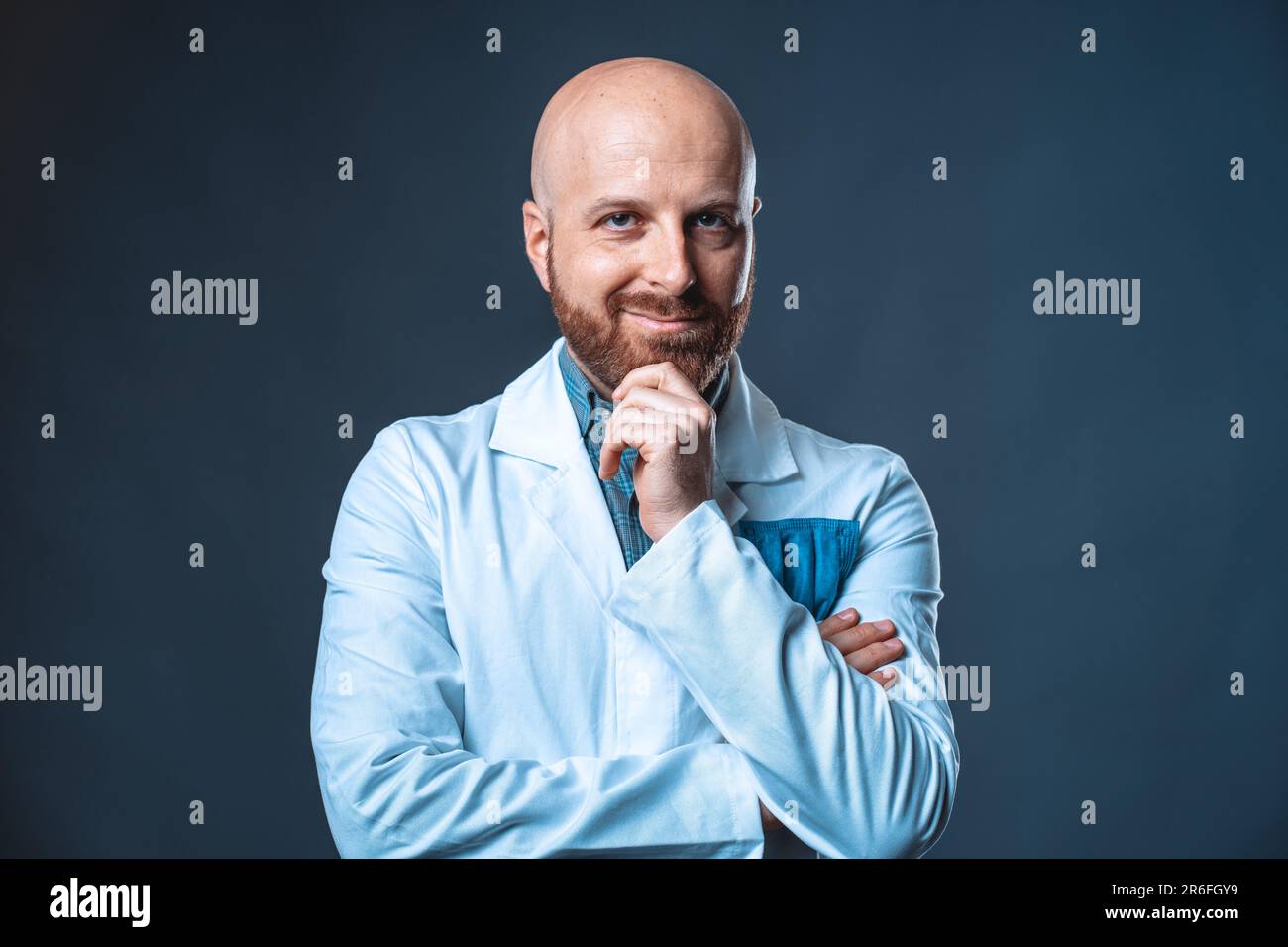 Photo of cheerful doctor with beard posing and smiling at camera with ...