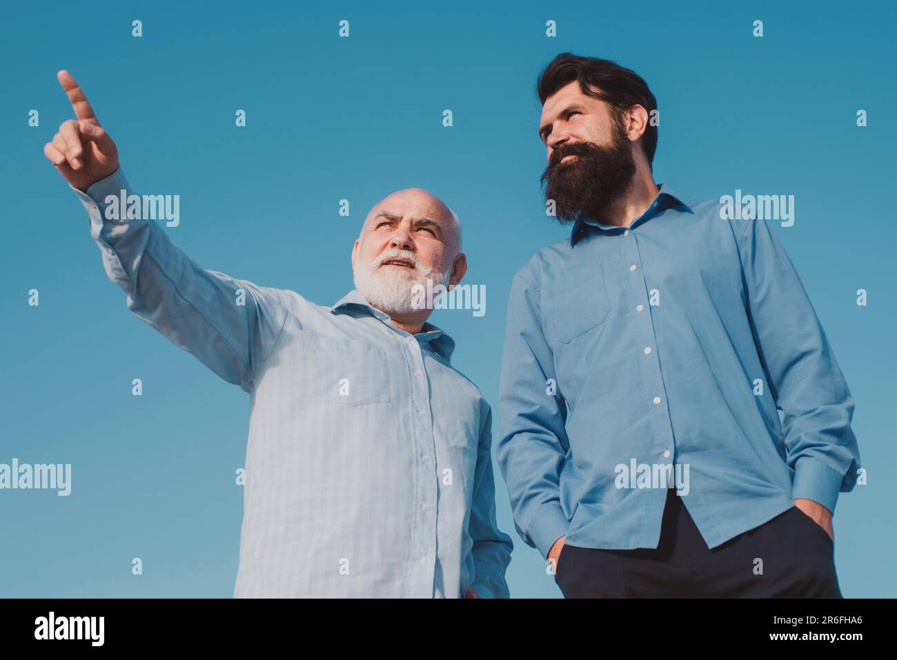 Happy grandfather and father over blue sky and clouds background. Men ...