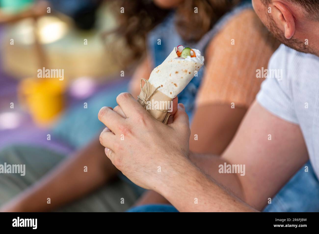 man is holding a vegan burrito in his hand beside a woman having good ...