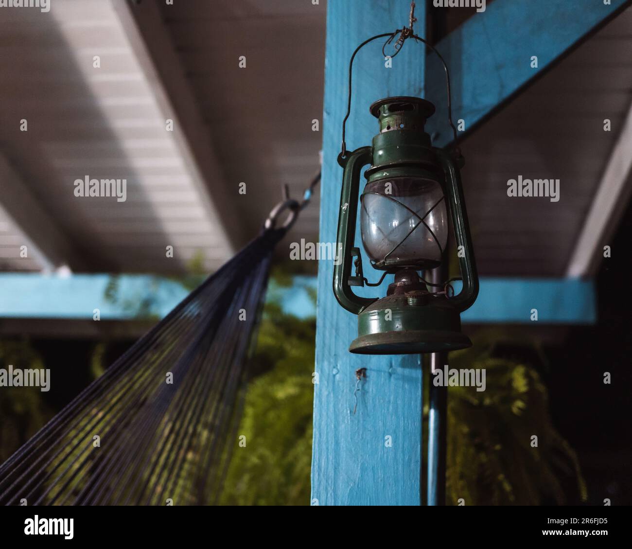 A metallic lantern, suspended from a wooden beam on the balcony of a ...