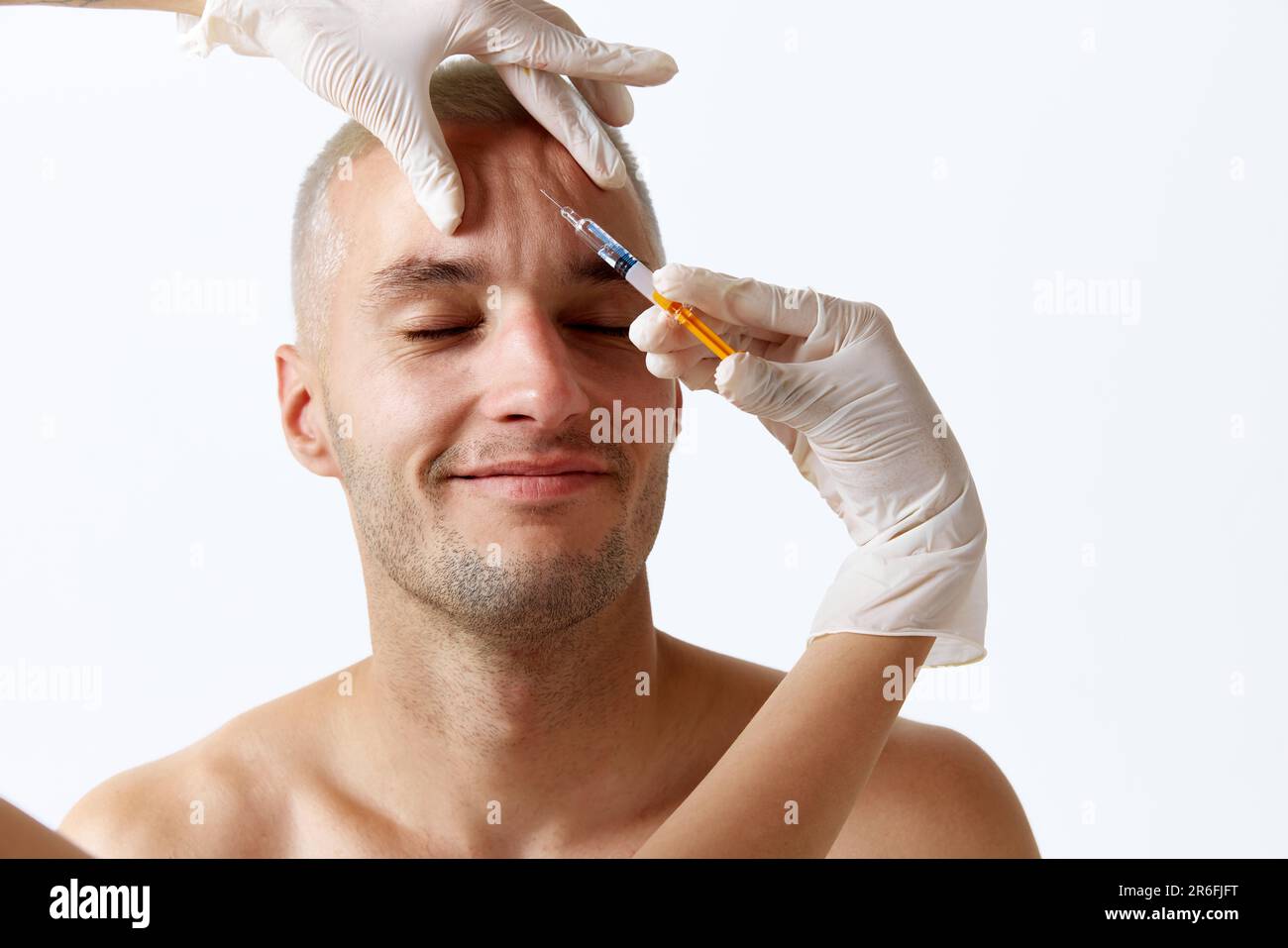 Handsome young man doing cosmetological face injections on forehead ...