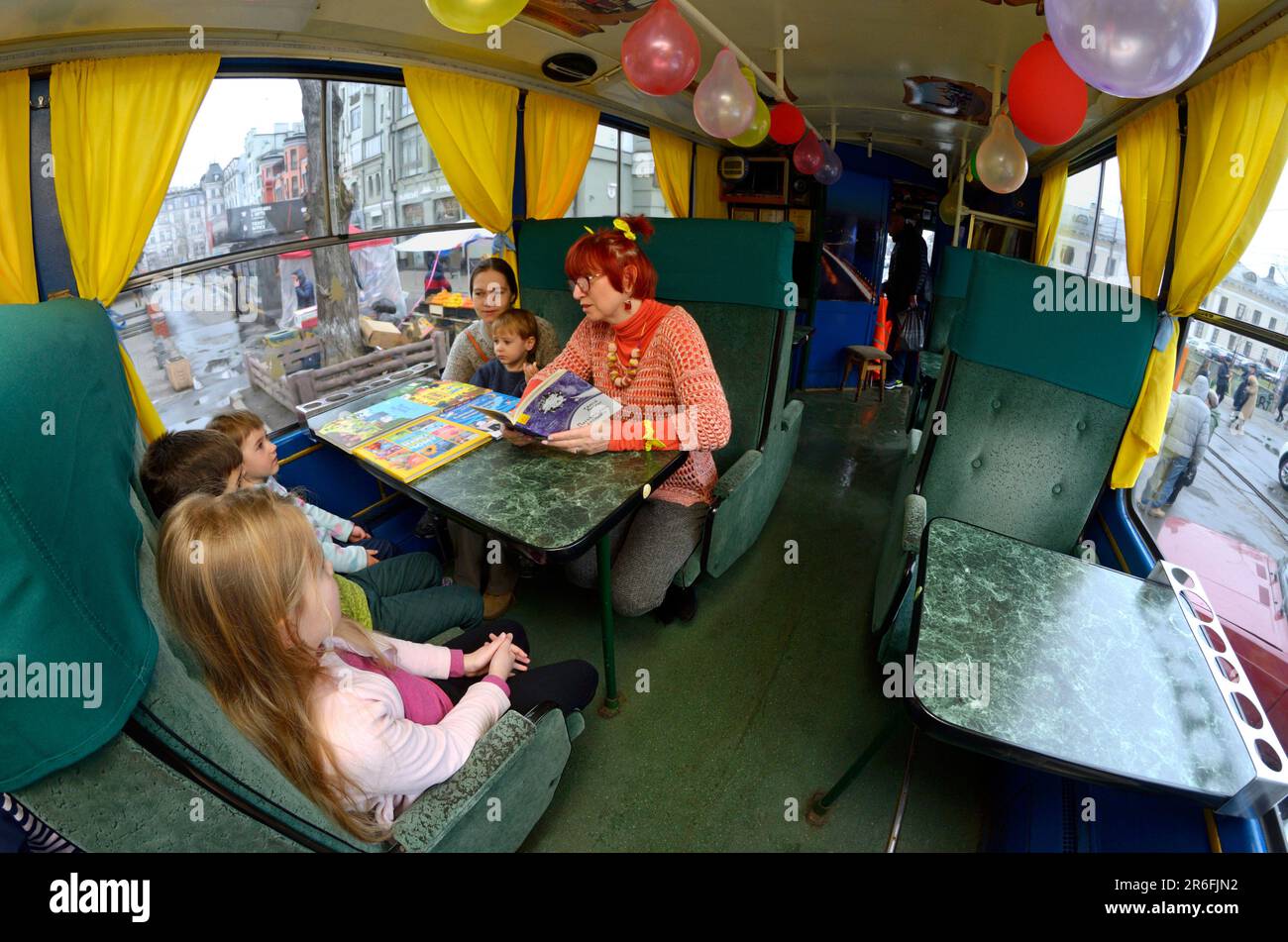 Teacher reading book for children in a tram compartment. Club and ...