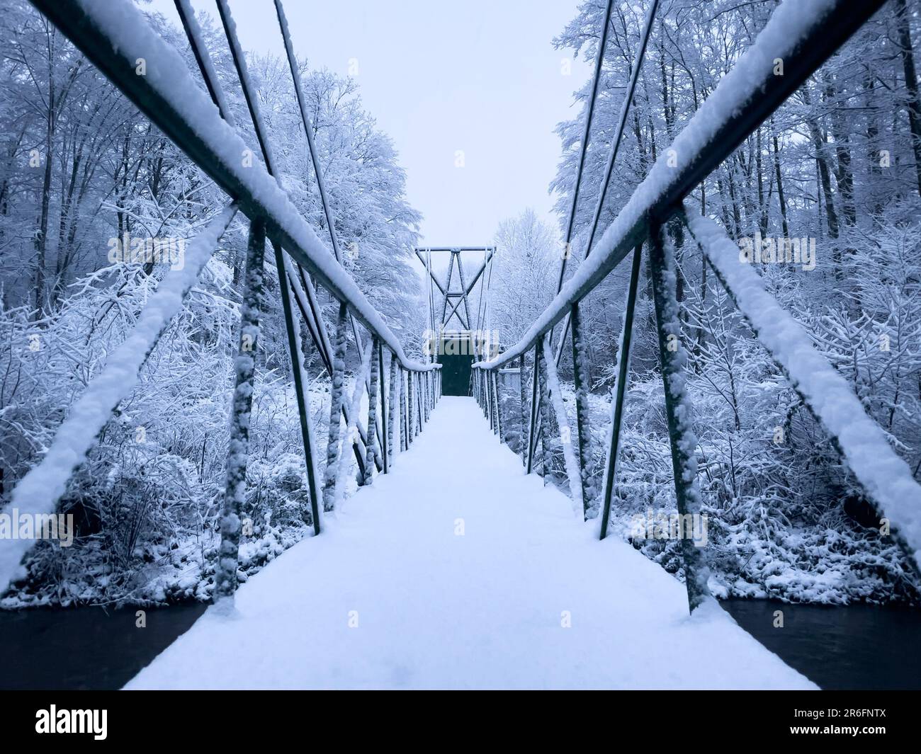 A snow-covered bridge spanning a frozen river below Stock Photo - Alamy