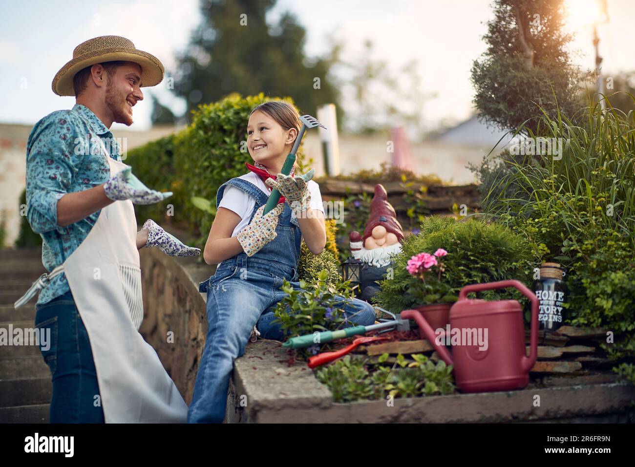 Young father with girl daughter working together in the flower garden ...