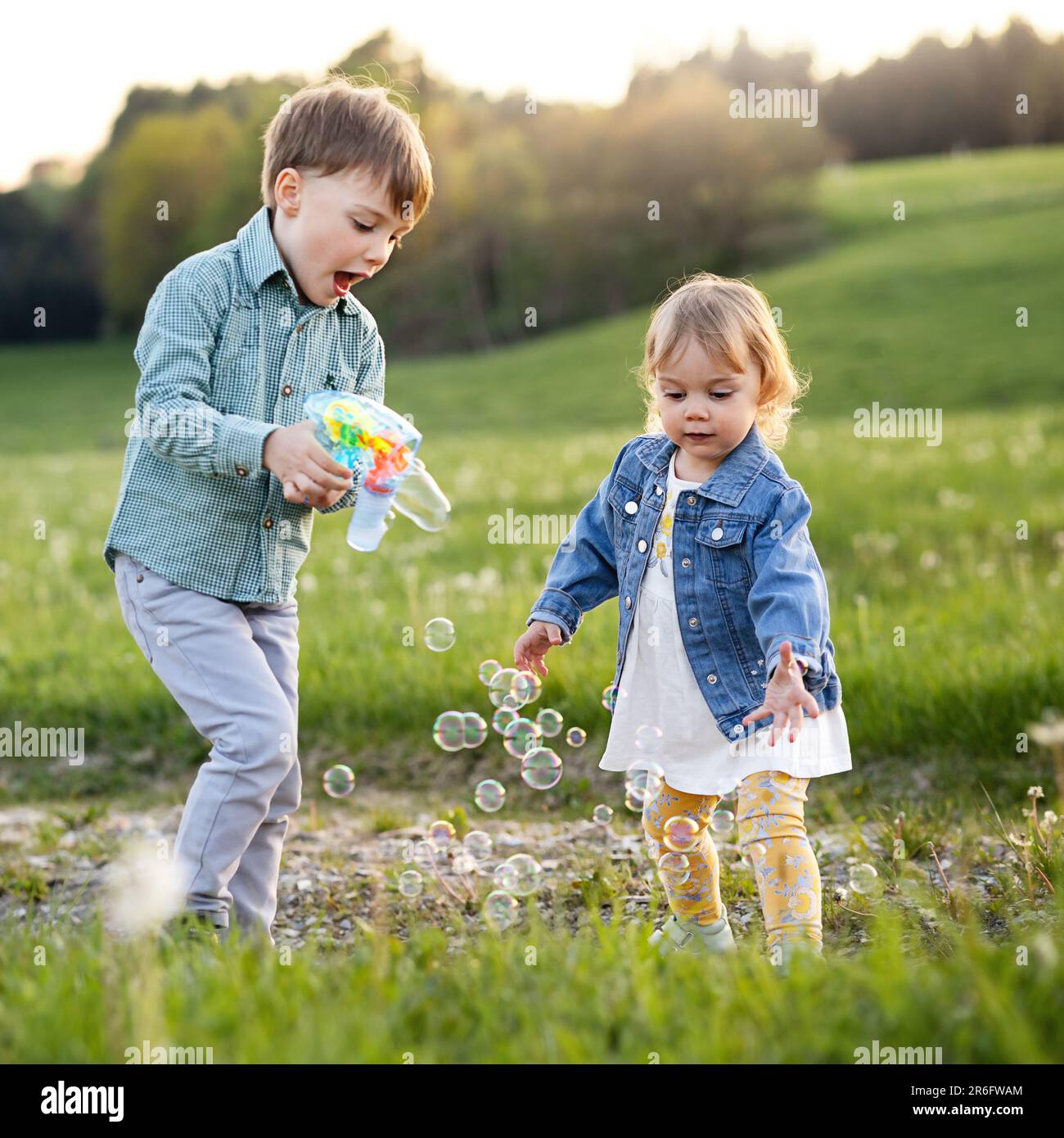 Summer greenery, a toy and two happy kids frolic on the lawn Stock ...