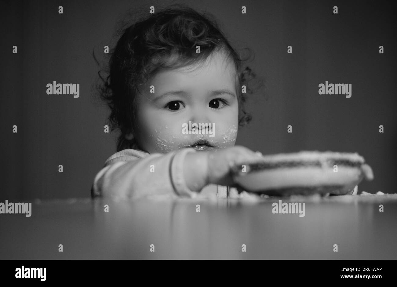 Cute baby with a spoon and a plate in the kitchen at home Stock Photo ...