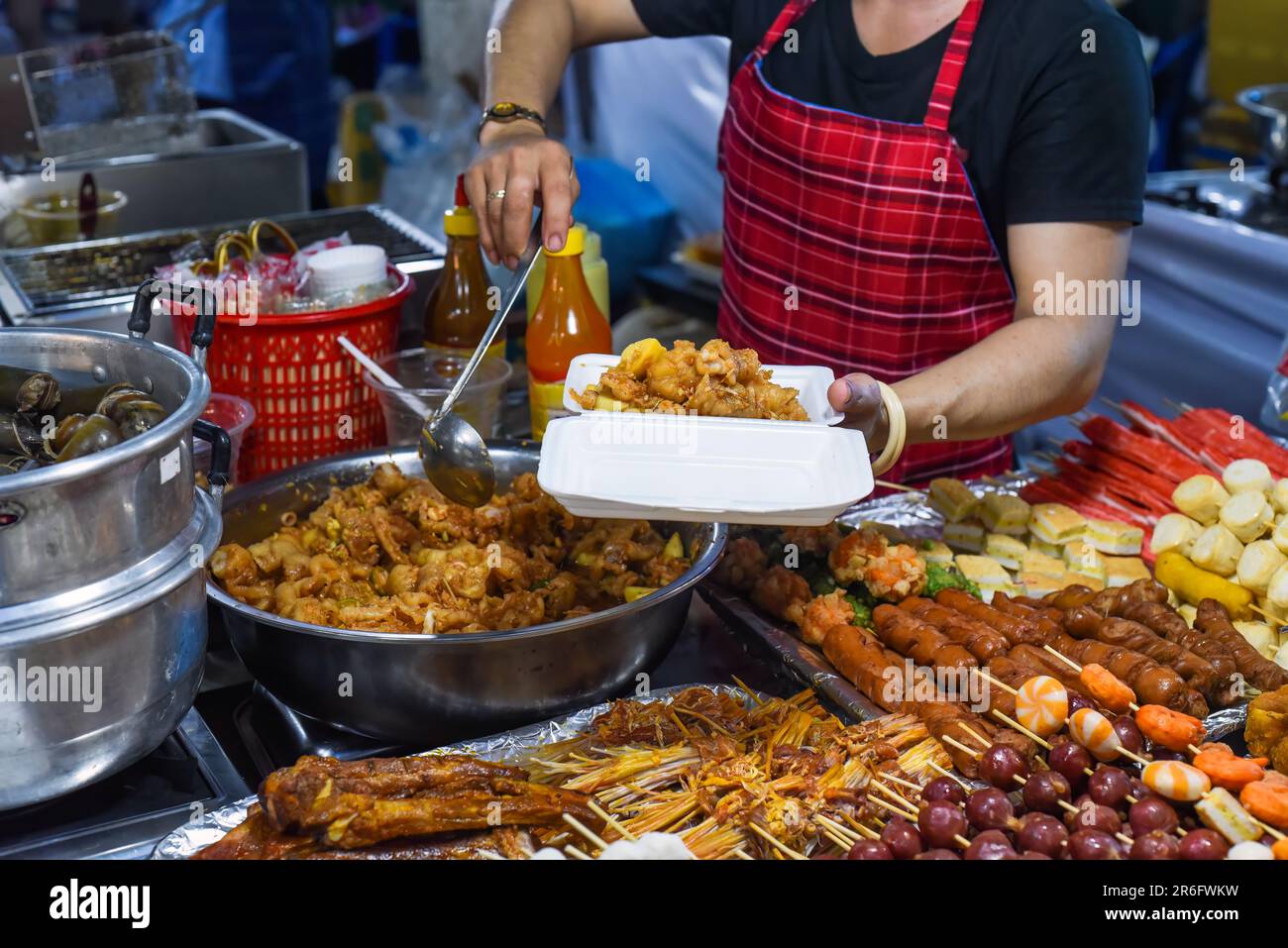 Vietnamese woman serving chicken paws in plastic box with chili in ...