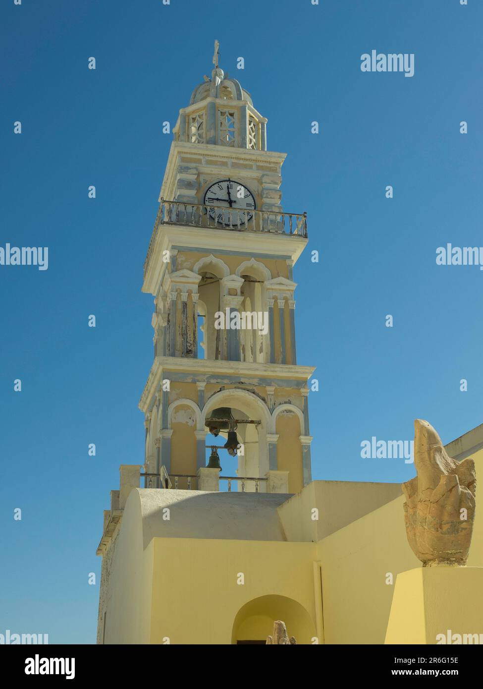 A large, white clock tower stands in front of a tall, stone tower in a ...