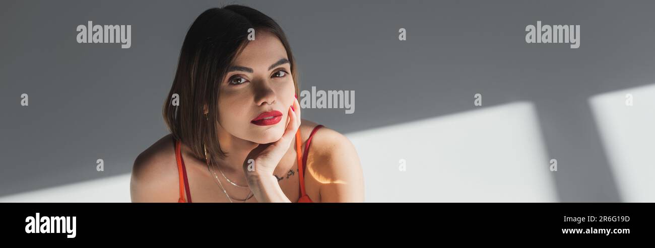 high angle view of young tattooed woman with short hair sitting on grey ...