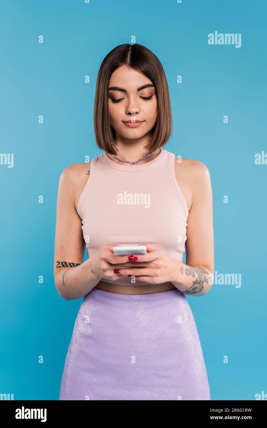 woman texting on smartphone, short hair, tattoos and nose piercing ...