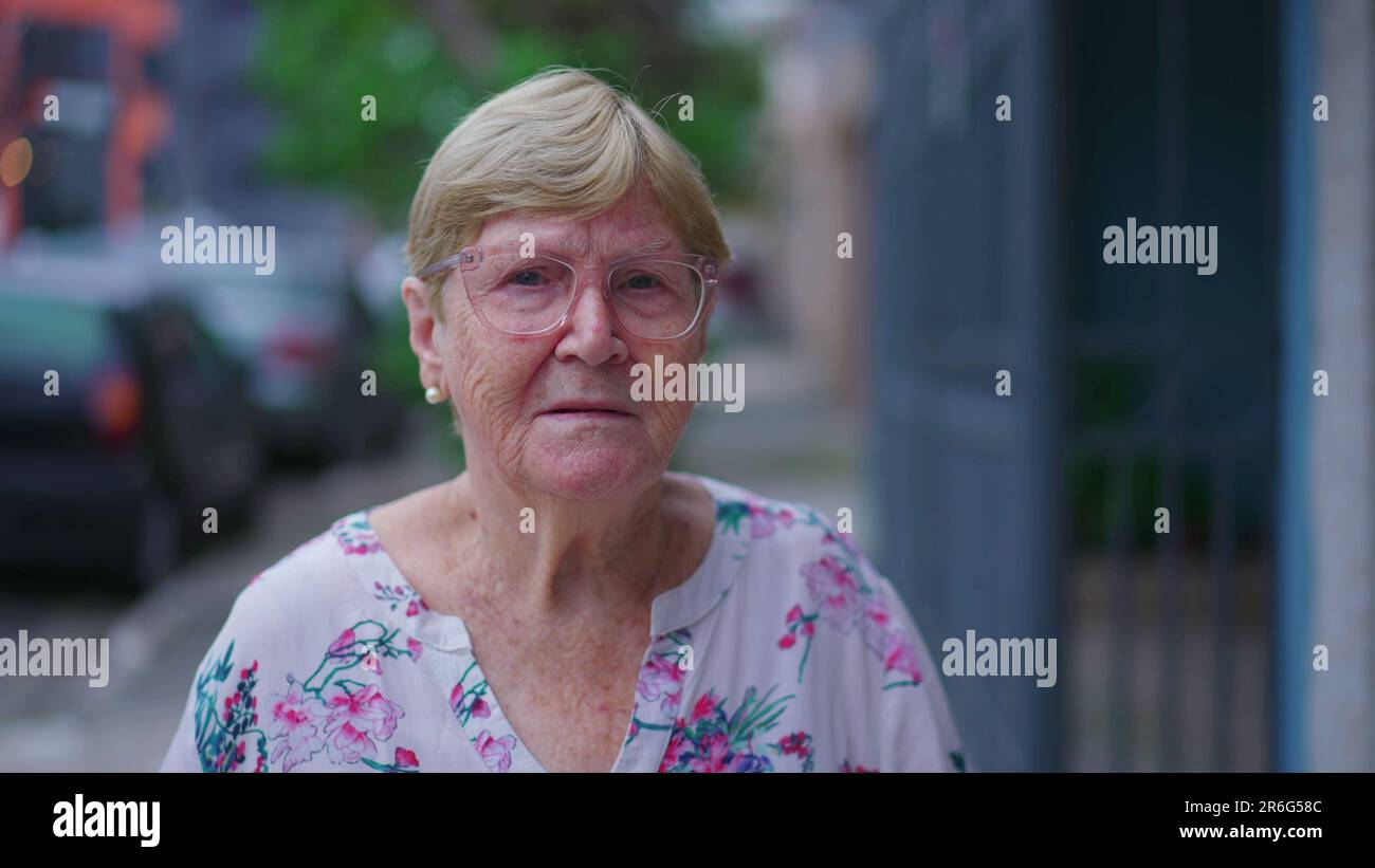 Portrait of an elderly senior woman close-up face standing in street ...