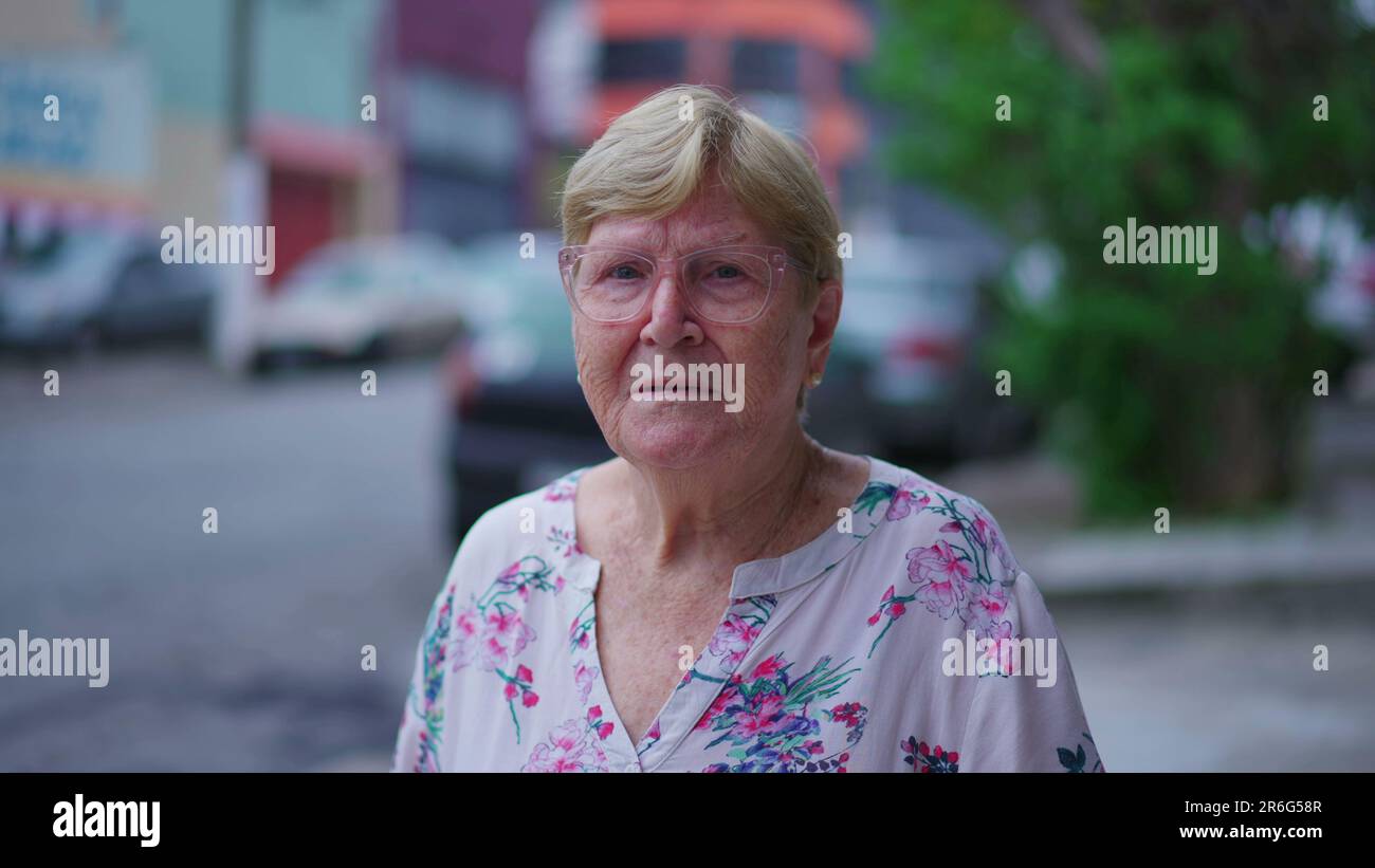 Portrait of an elderly senior woman close-up face standing in street ...