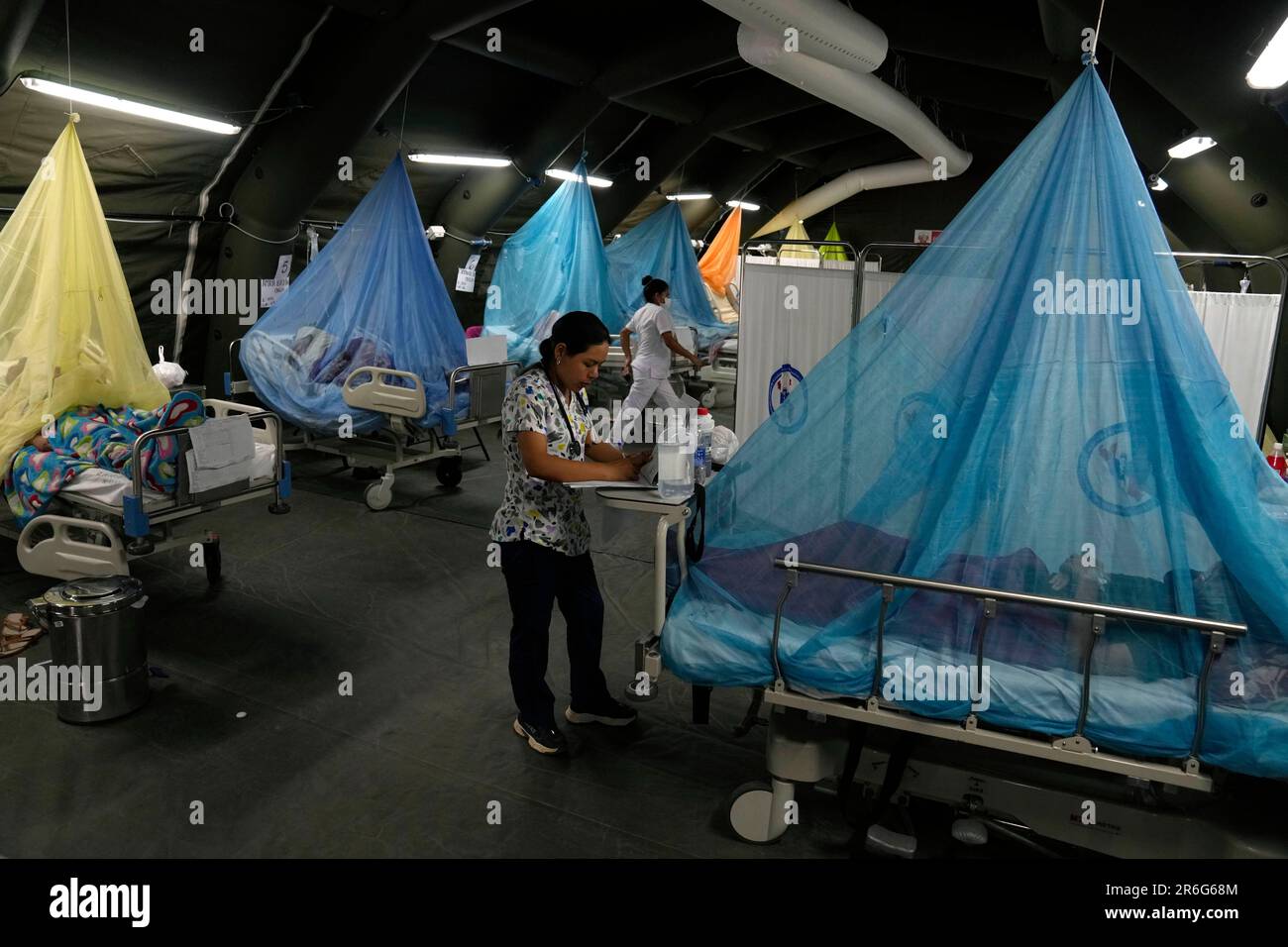 A doctor writes a prescription as patients suffering from dengue lie in ...