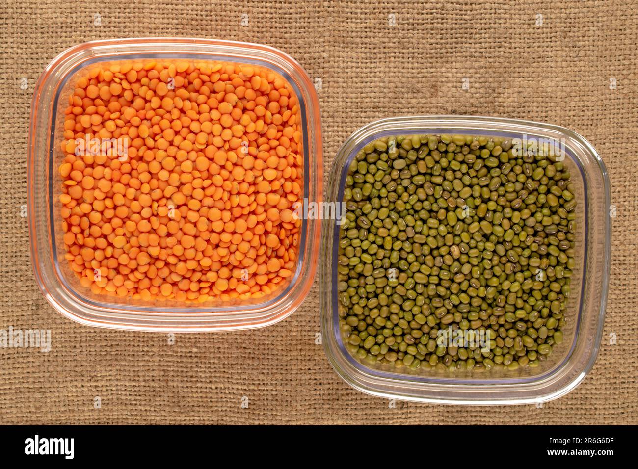 Red lentils and mung beans in plastic containers on jute cloth, macro ...