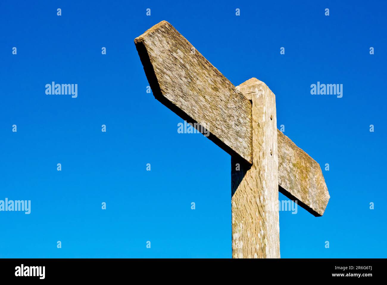 A blank, directionless wooden signpost isolated against a clear blue ...