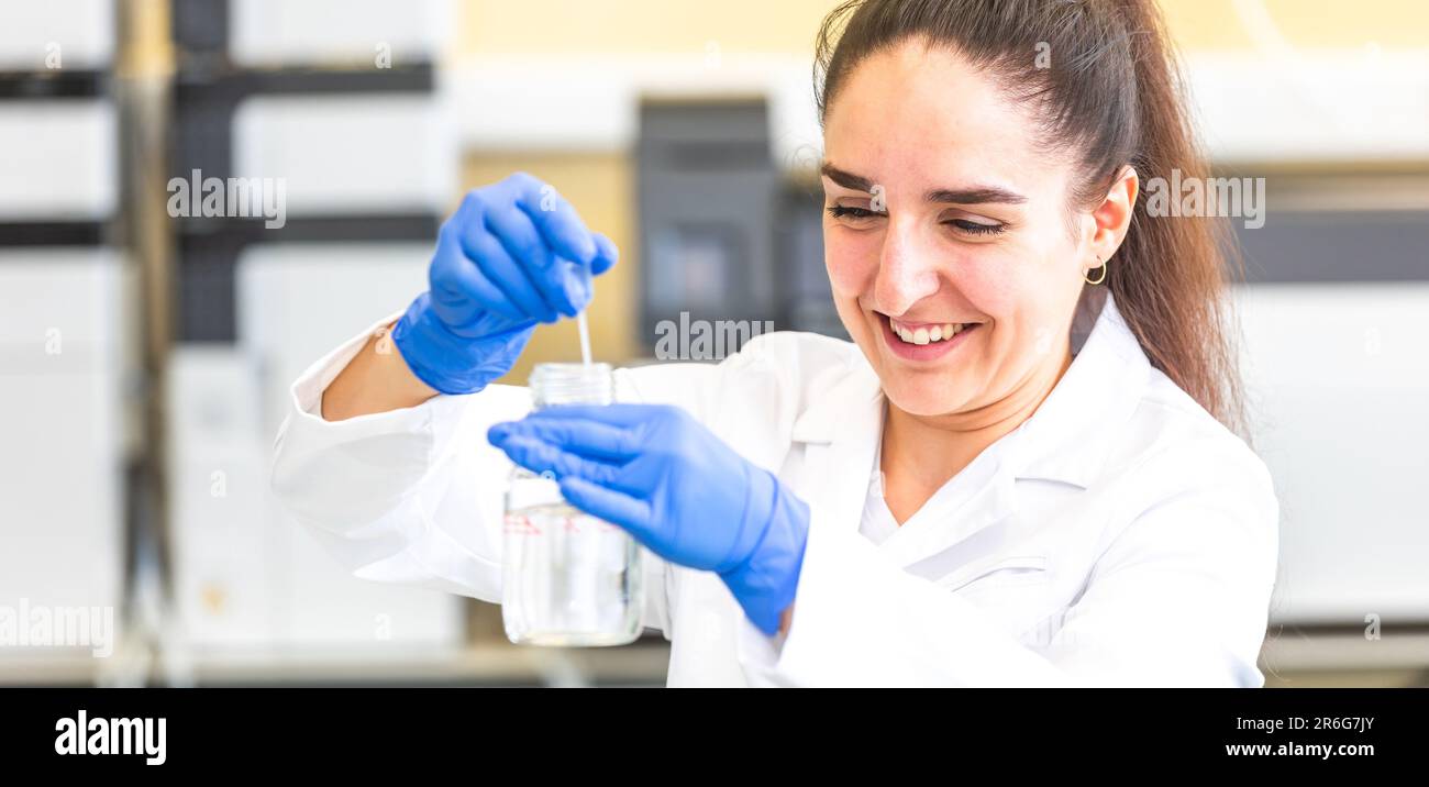 Scientist with dropper dripping liquid into a test tube in scientific ...