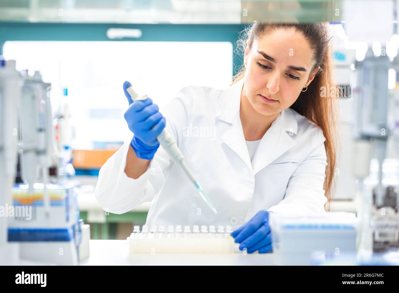 Scientist with dropper dripping liquid into a test tube in scientific ...