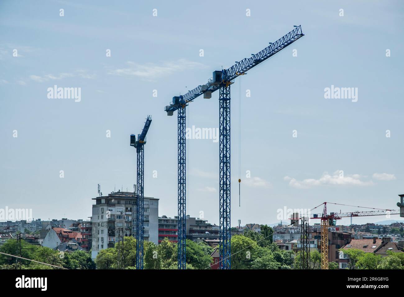Tall construction tower cranes on cityscape background Stock Photo - Alamy