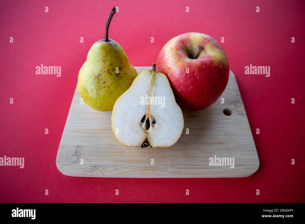 Sliced pear and apple on cutting board with red background Stock Photo ...