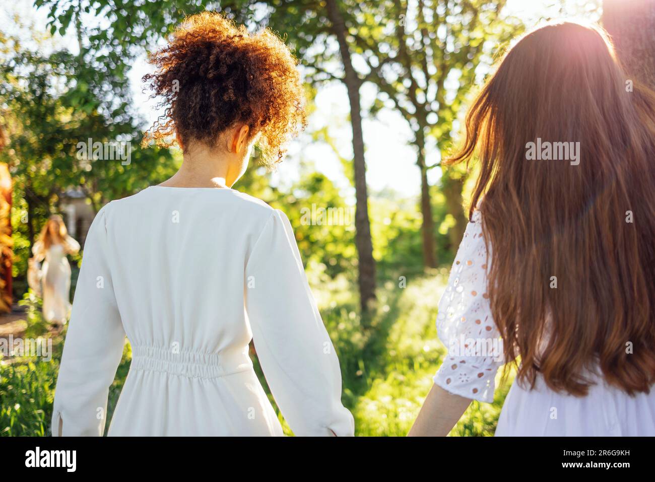 Three pretty female multiracial teenagers in white elegant dresses are ...