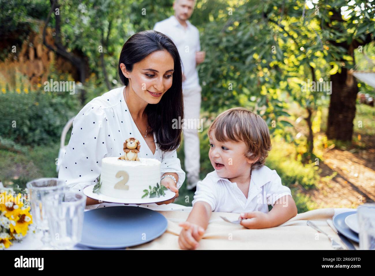 Little cute kid and his parents are tasting festive cake outdoors in ...