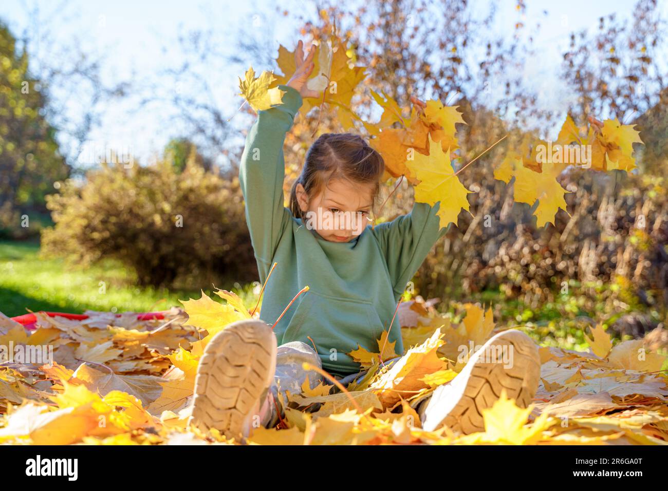 Girl kid jumping on trampoline with autumn leaves. Bright yellow orange ...